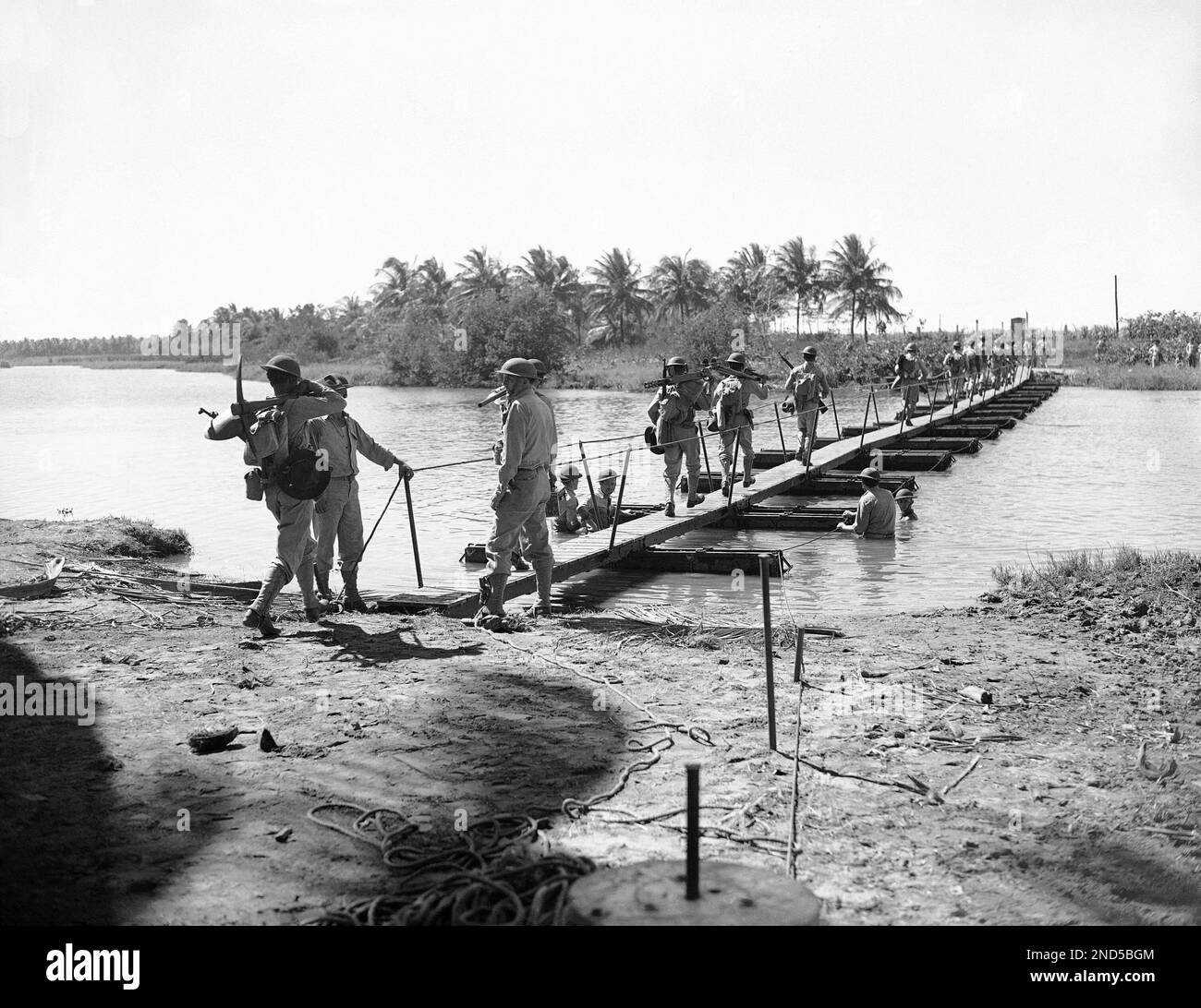 Puerto Rican soldiers of the American army walk across a bridge, which ...