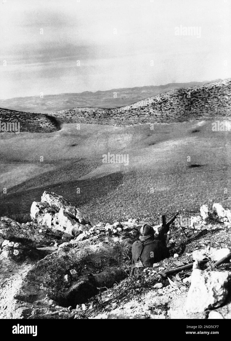 A steel-helmeted French machine gunner on a hill outpost watches for ...