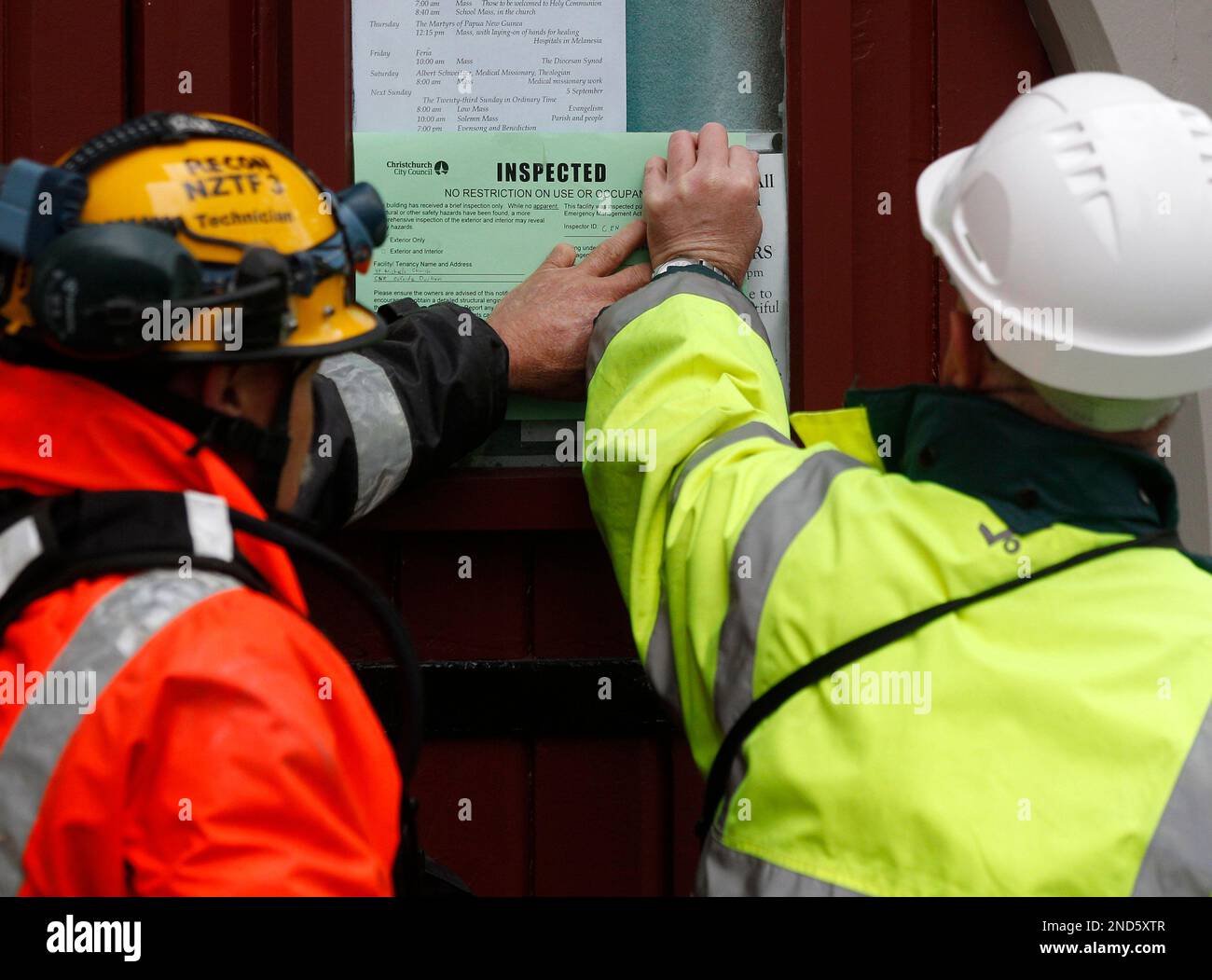 Inspectors from the New Zealand Urban Search and Rescue force paste a ...