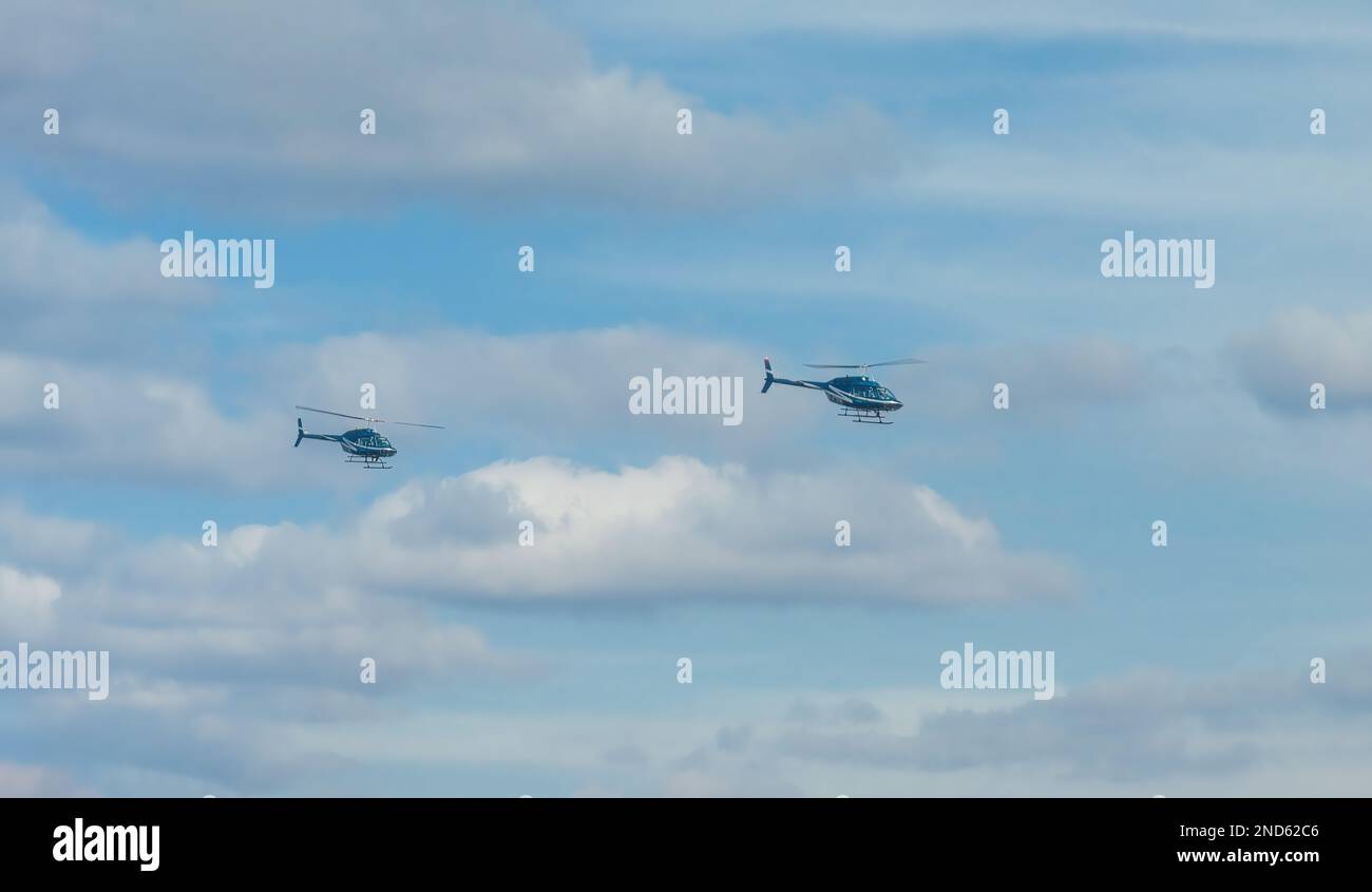 two helicopters flying high in the blue sky Stock Photo - Alamy