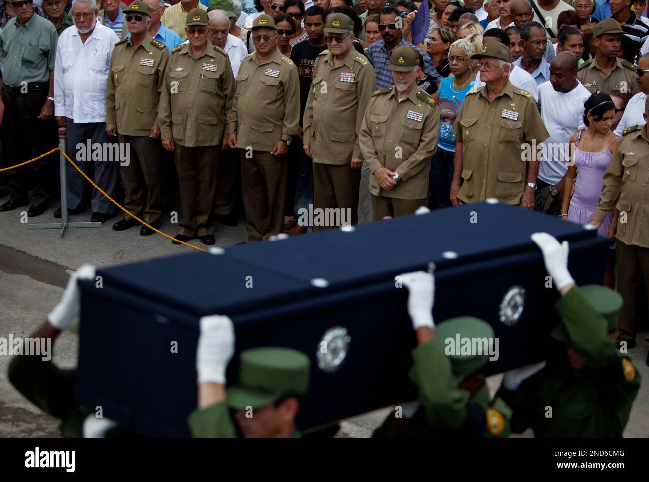 Military members and government officials watch soldiers carry a coffin ...