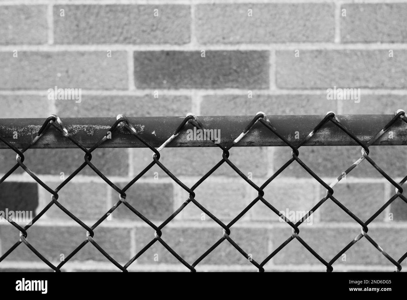 Typical common metal chain link fence running along the brick wall in a ...