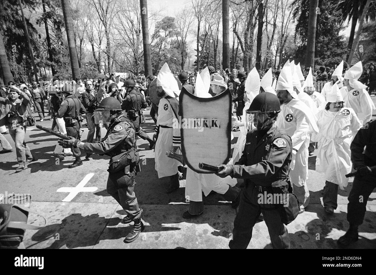 San Jose police officers escort about 20 white-robed Ku Klux Klansmen ...