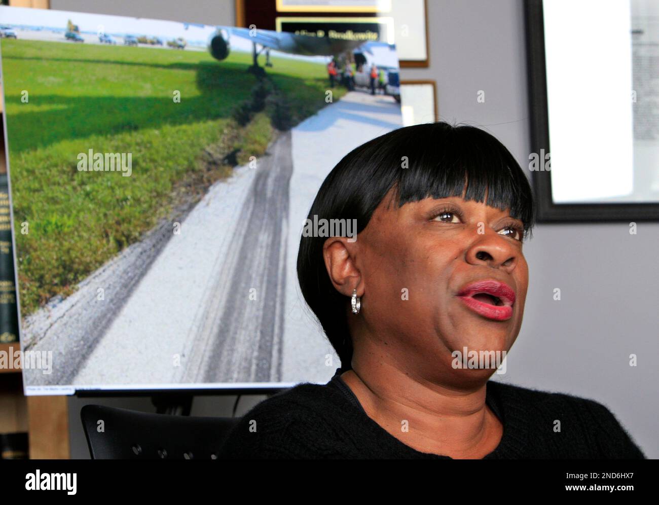 Jewel Thomas sits in front of a photo of skids marks leading to the ...