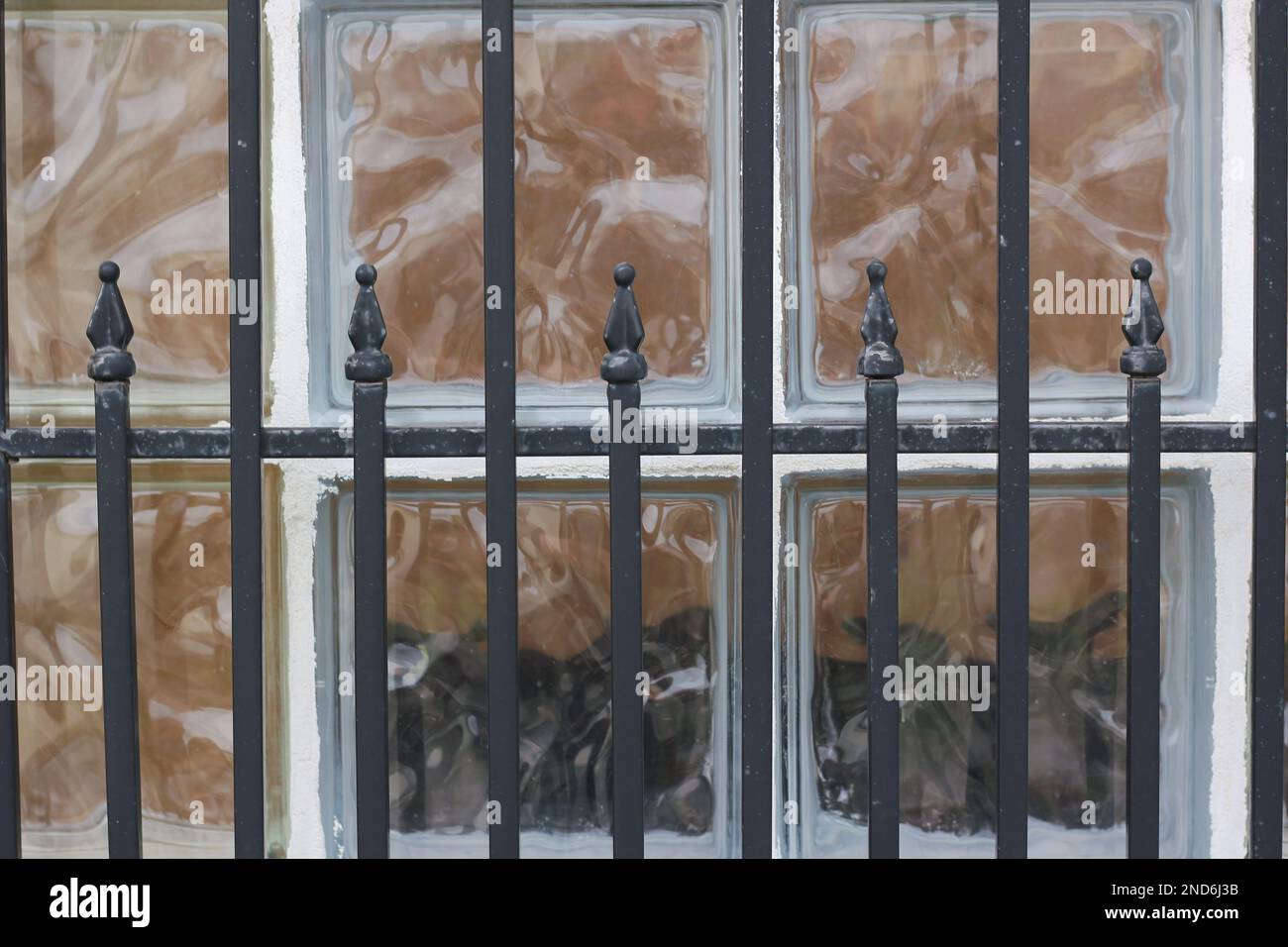 Black metal wrought iron fence guarding a glass block window Stock ...