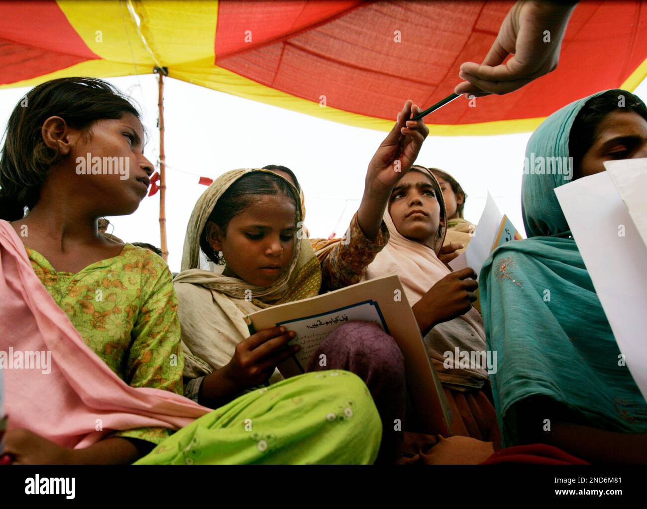 A Pakistani teacher hands out colored pencils to children living at a ...