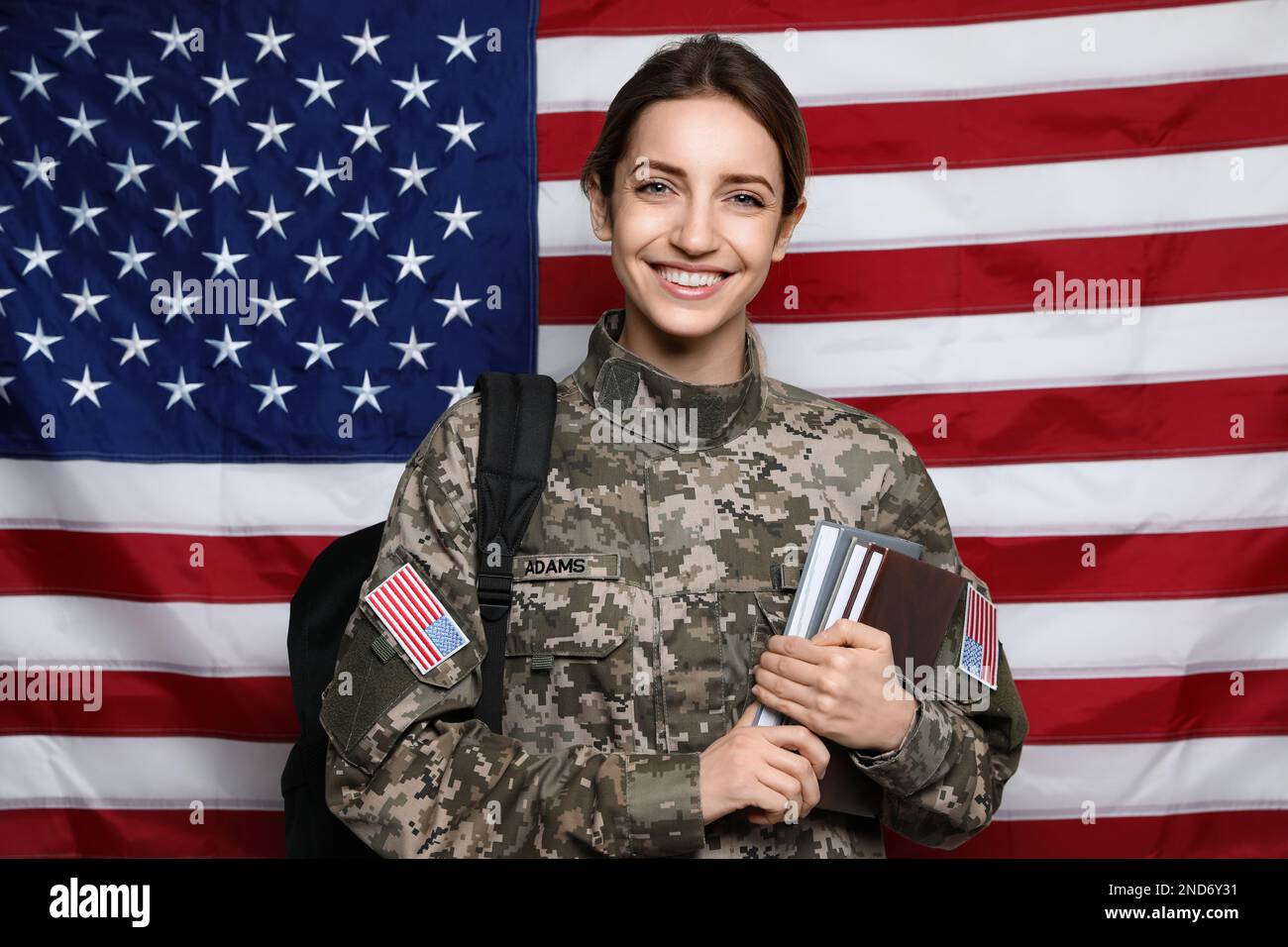 Female cadet with backpack and books against American flag. Military ...