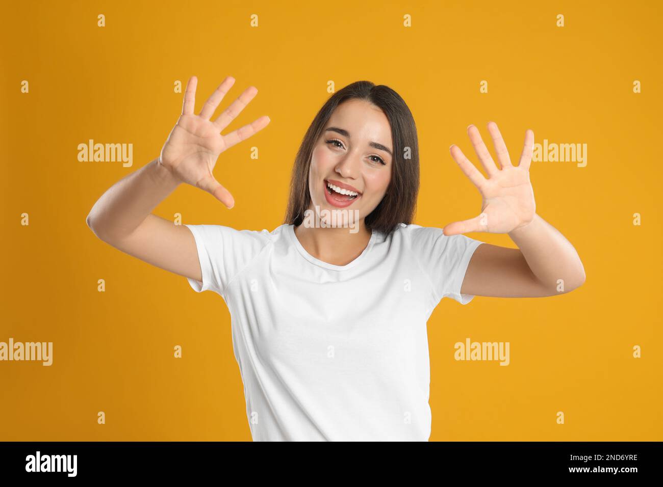 Woman in white t-shirt showing number ten with her hands on yellow ...