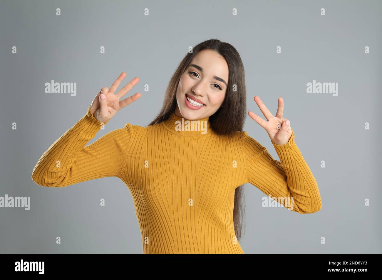 Woman in yellow turtleneck sweater showing number six with her hands on ...