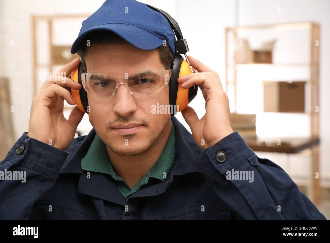 Worker wearing safety headphones indoors. Hearing protection device ...
