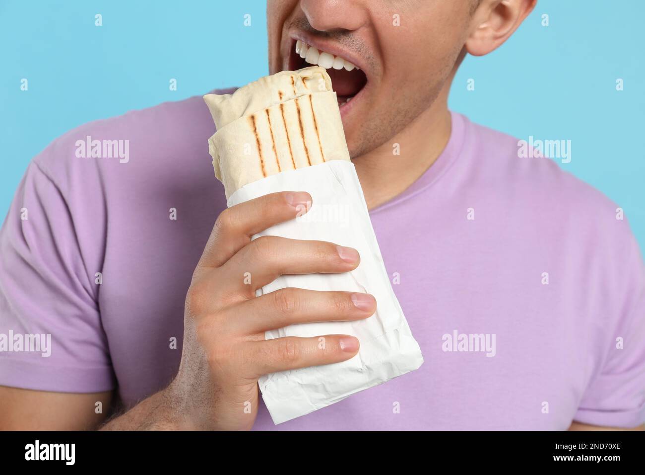 Man eating delicious shawarma on turquoise background, closeup Stock ...