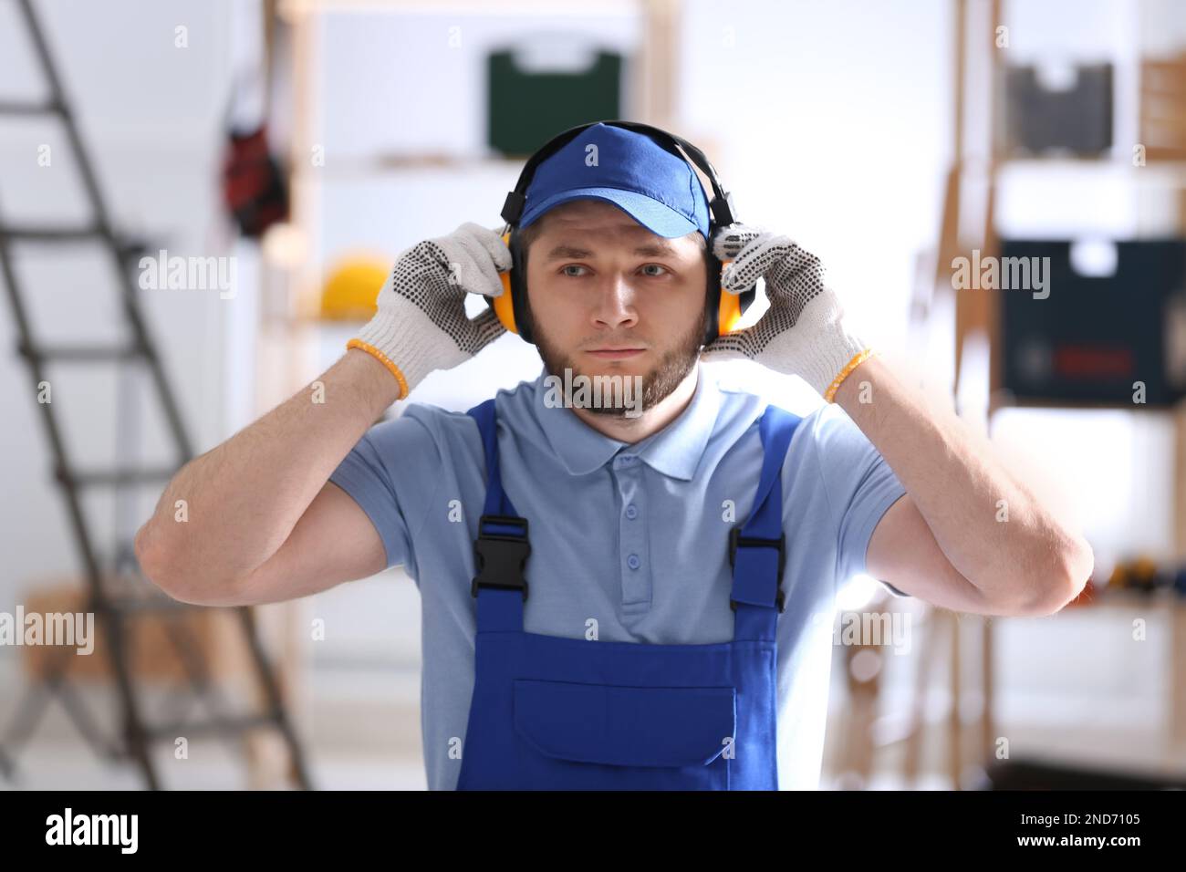 Worker wearing safety headphones indoors. Hearing protection device ...