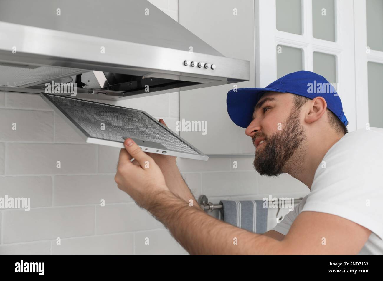 Worker repairing modern cooker hood in kitchen Stock Photo - Alamy