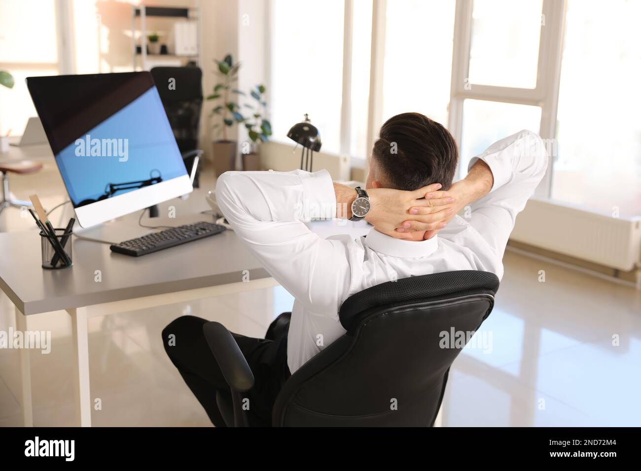 Businessman relaxing in office chair at workplace, back view Stock ...