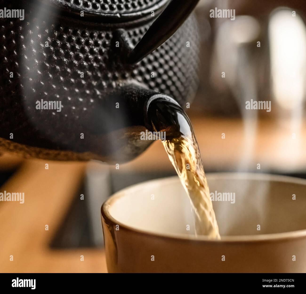 Pouring hot black tea from metal teapot Stock Photo - Alamy