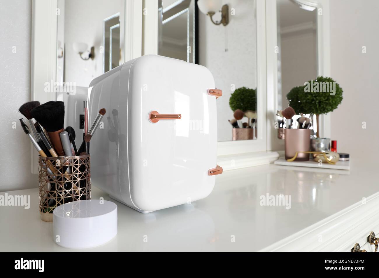 Mini fridge for cosmetic products on white vanity table Stock Photo - Alamy