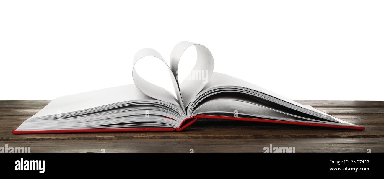 Open book with pages folded in heart on wooden table against white ...