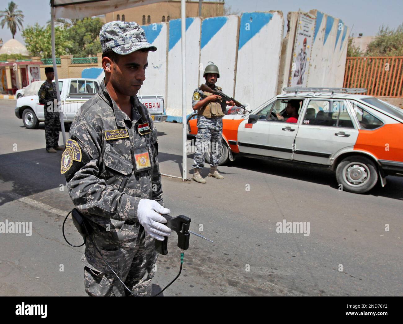 An Iraqi police officers uses a bomb detector at a checkpoint in ...