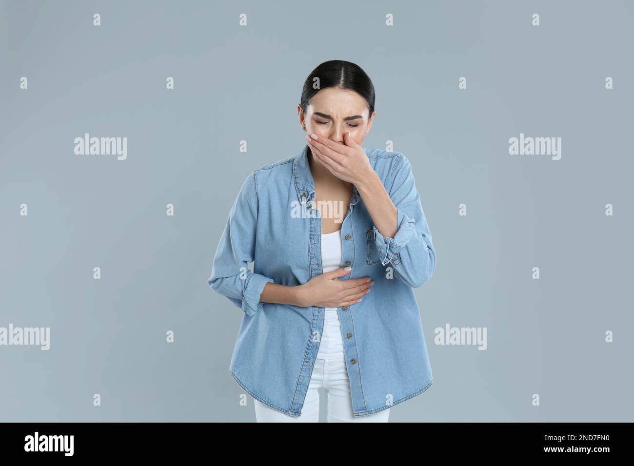 Woman suffering from stomach ache and nausea on grey background. Food ...