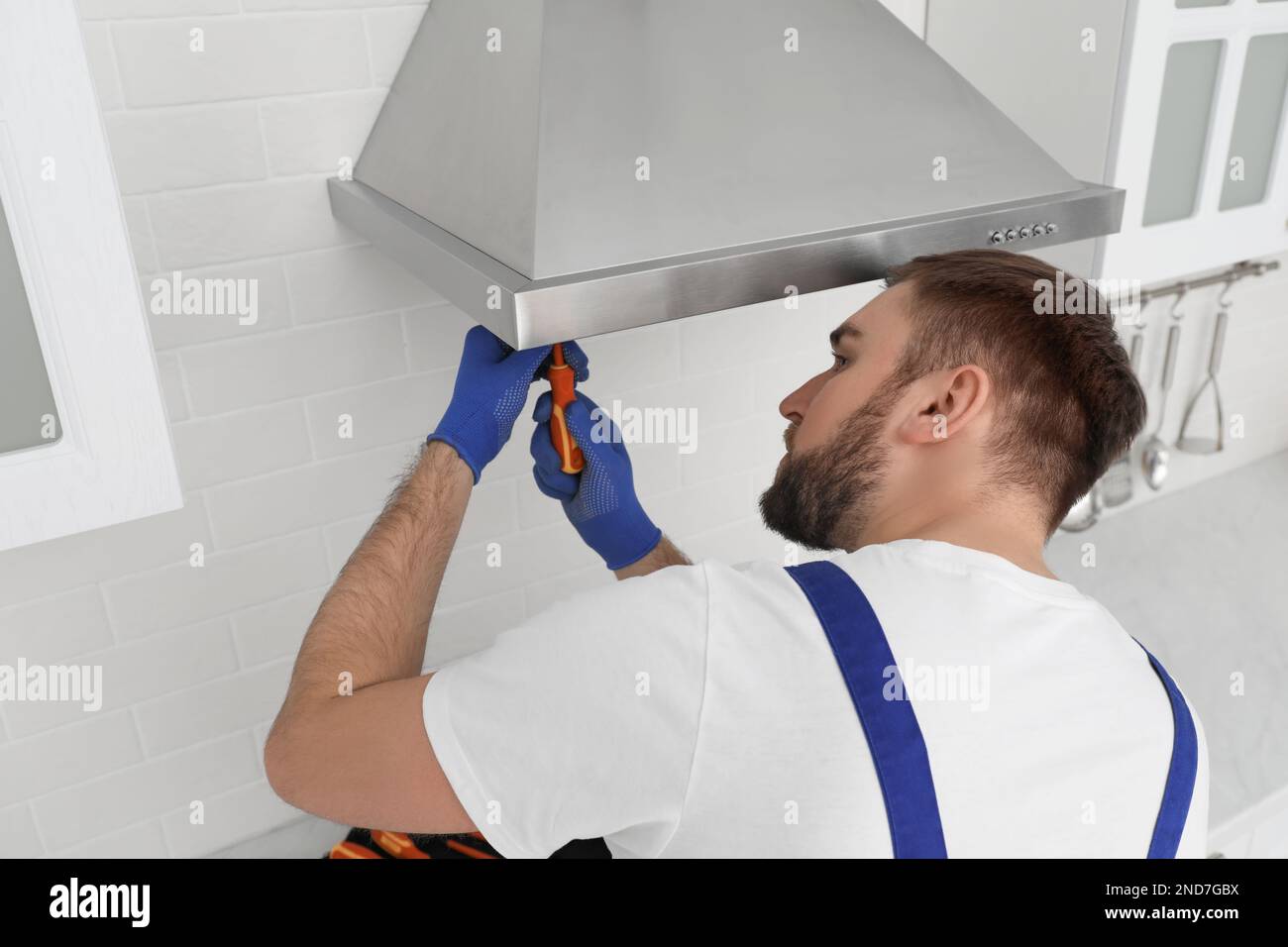 Worker repairing modern cooker hood in kitchen Stock Photo - Alamy