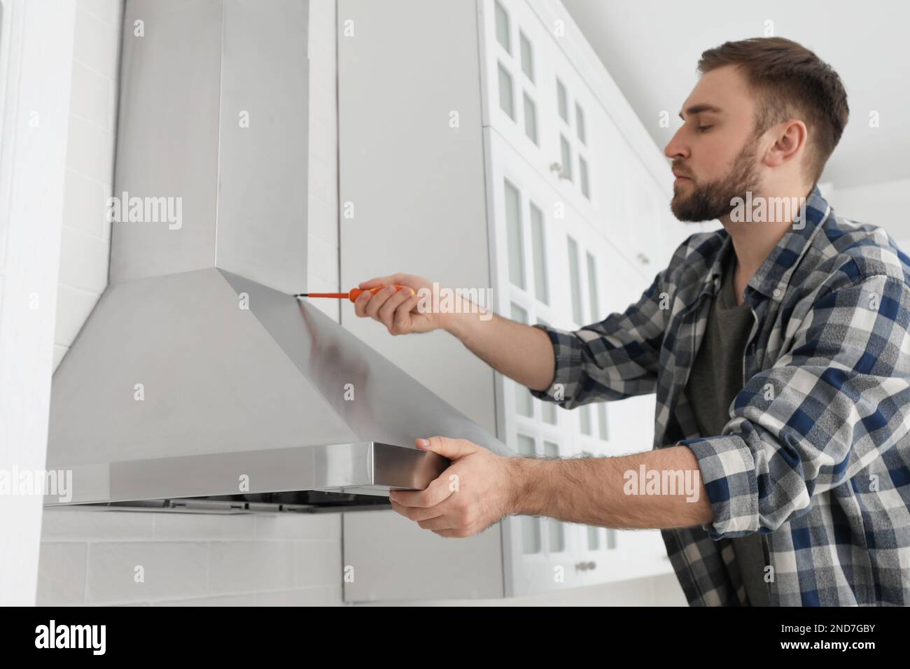 Man repairing modern cooker hood in kitchen Stock Photo - Alamy