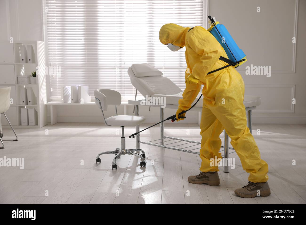 Man in protective suit sanitizing doctor's office. Medical disinfection ...
