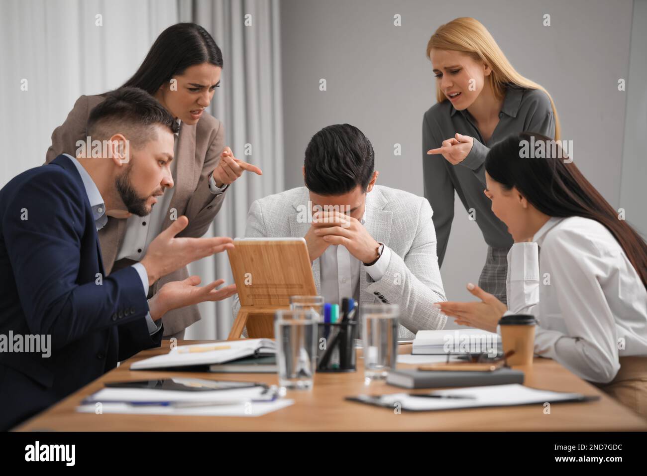 Coworkers bullying their colleague at workplace in office Stock Photo ...