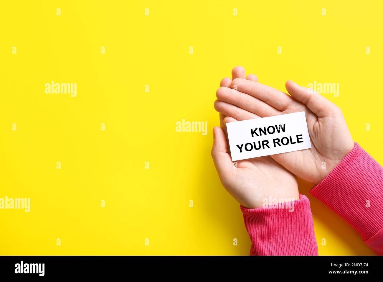 Woman holding card with phrase Know Your Role on yellow background, top ...