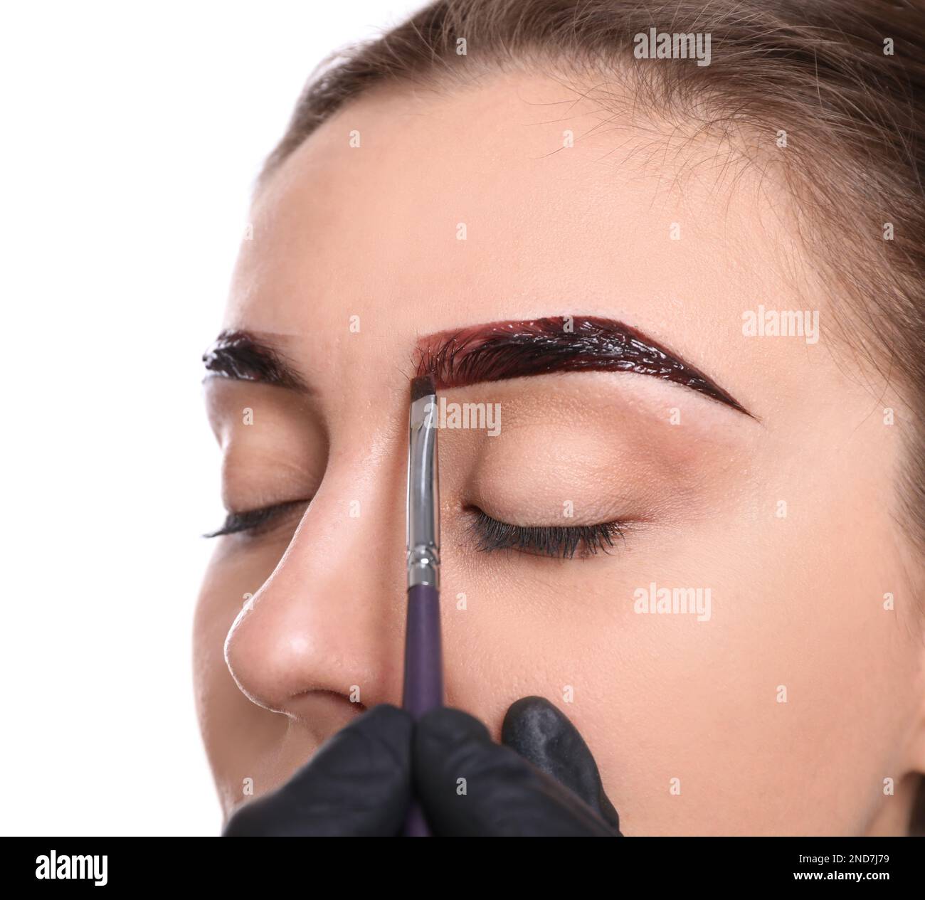 Beautician applying tint during eyebrows correction procedure on white ...