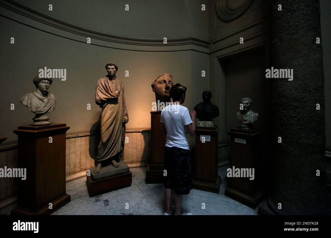 A tourist looks at statues watched by security monitoring cameras ...