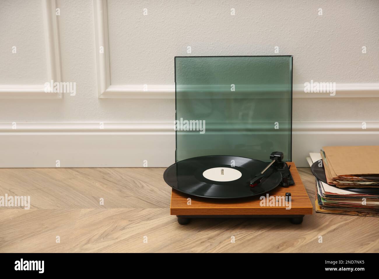 Stylish turntable and vinyl records on floor indoors, space for text ...