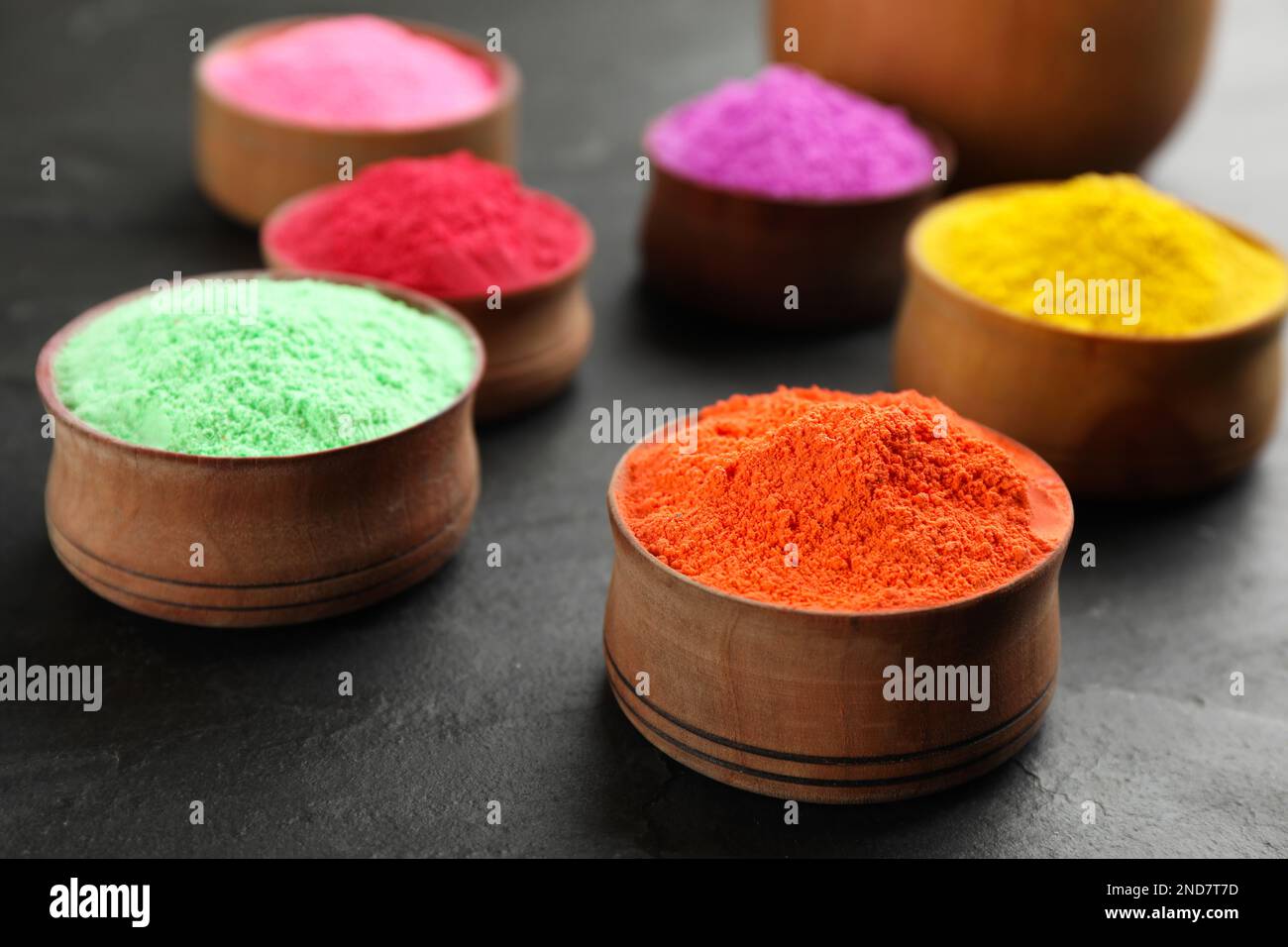 Colorful powder dyes in bowls on black background, closeup. Holi ...
