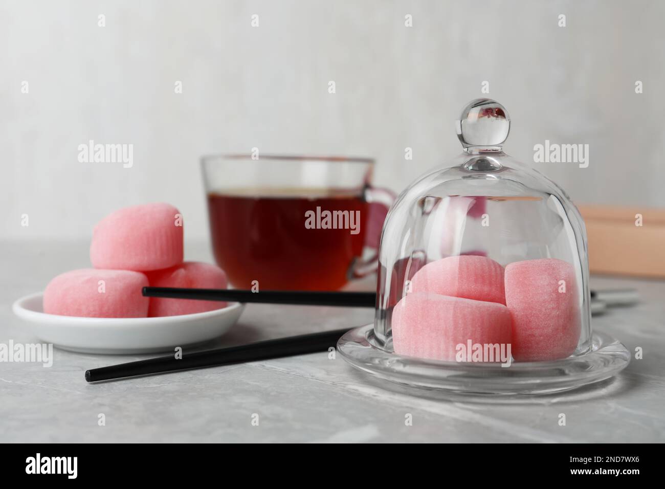 Glass cloche with delicious mochi on grey table, space for text ...