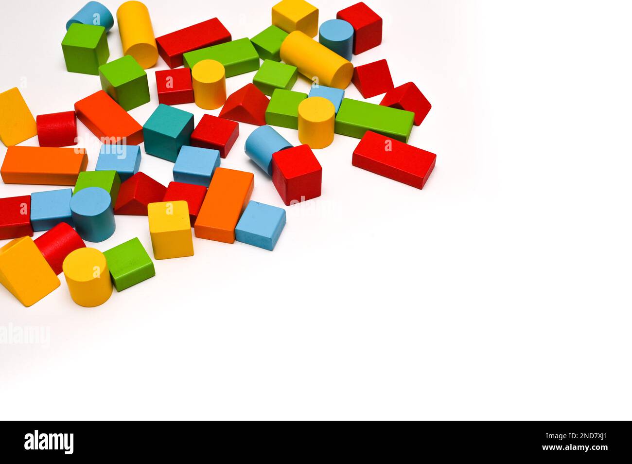 Colorful wooden bricks of different shapes on a white wooden table. The ...