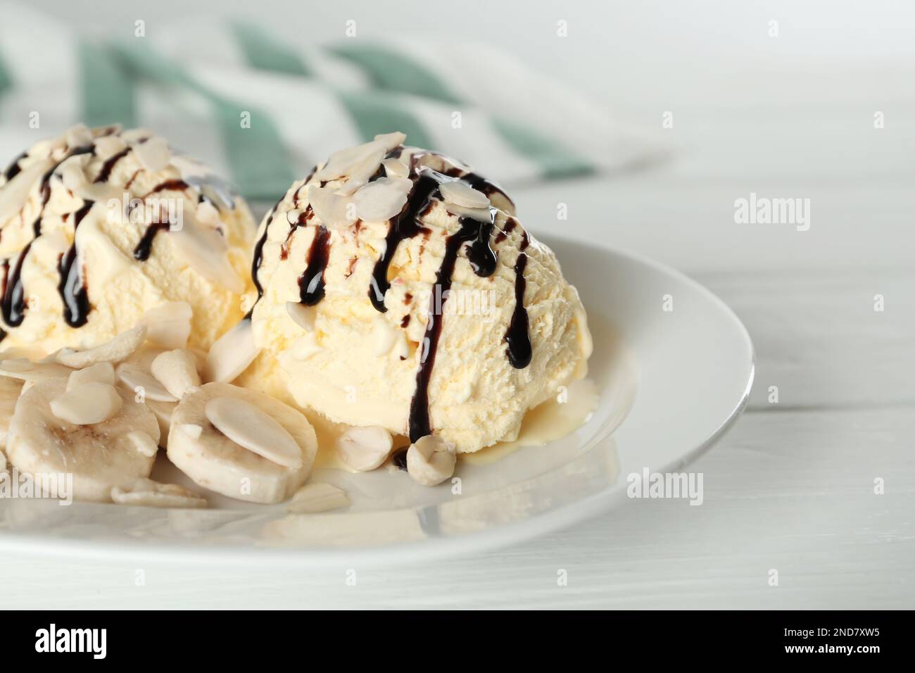 Delicious banana ice cream with toppings on white wooden table, closeup ...