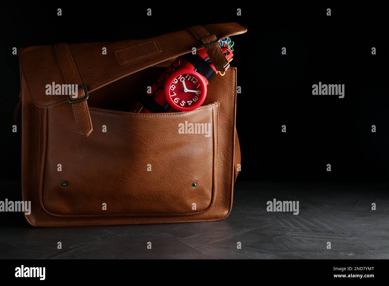 Leather briefcase with dynamite time bomb on grey table against black ...