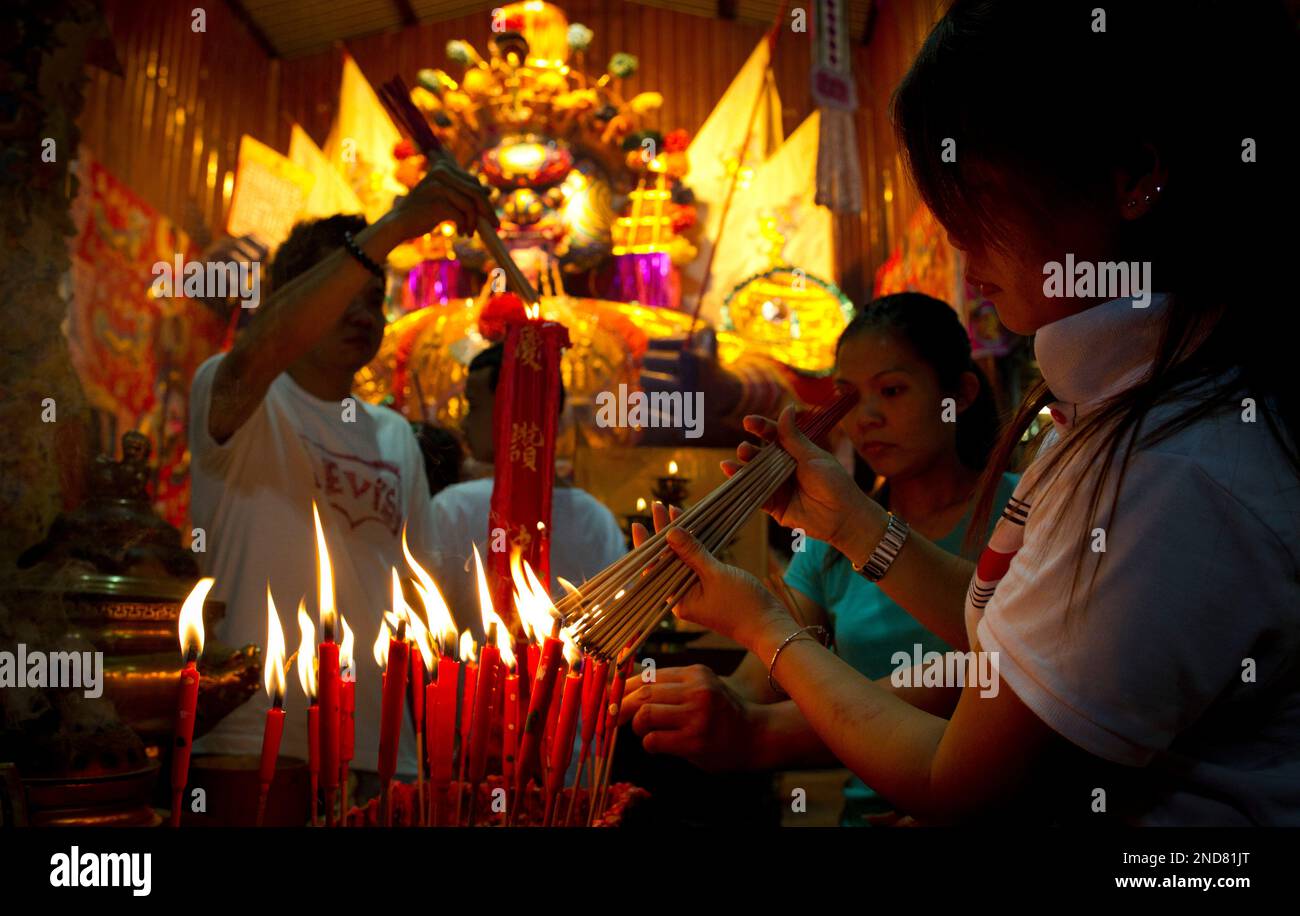 Ethnic Chinese burns joss sticks infront of a 26 foot-high giant paper ...