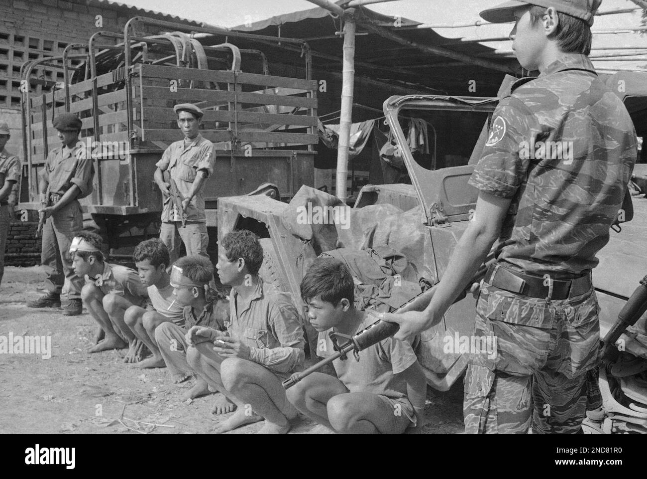 Cambodian soldiers guard a group of young men wounded and captured during fighting along Route 1 ...