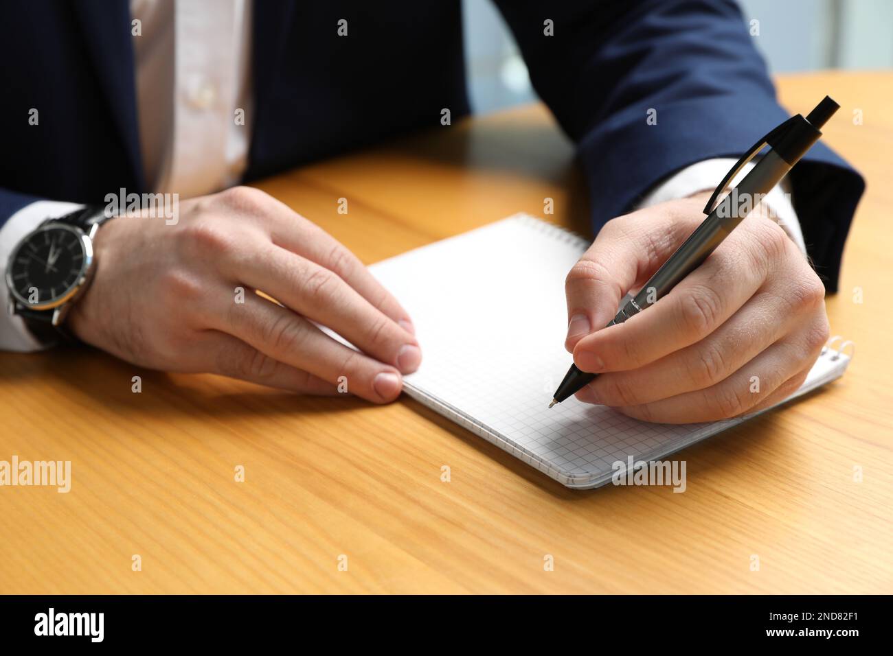 Left-handed man writing in notebook at wooden desk, closeup Stock Photo ...