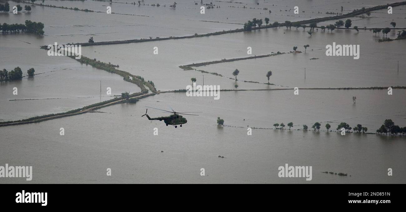 A Pakistan Army helicopter flies over flood waters near Thul, in Sindh ...