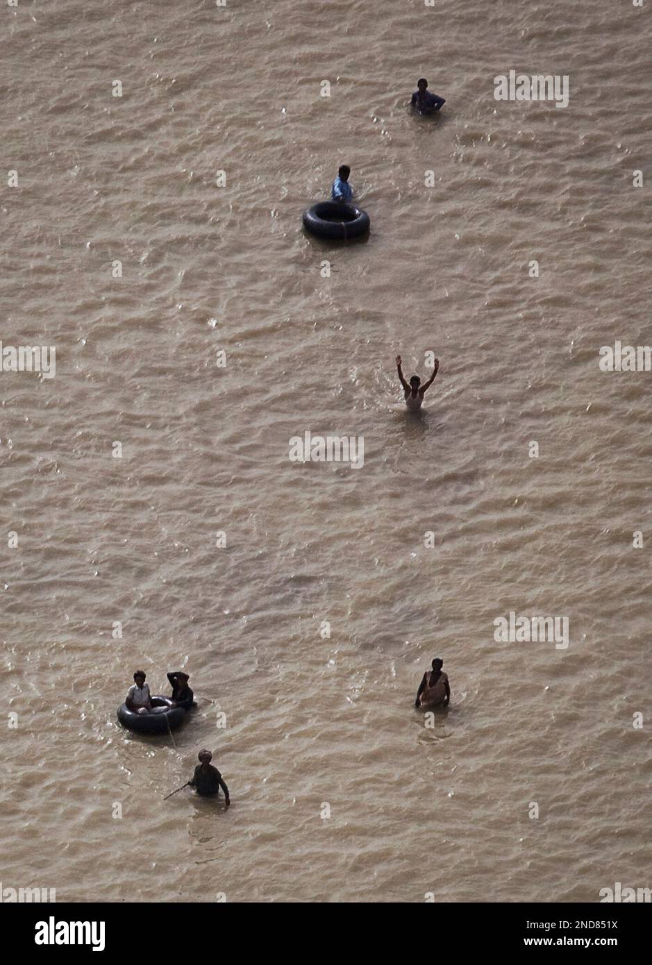 Pakistani residents swim and float as they wait for an air drop of food ...