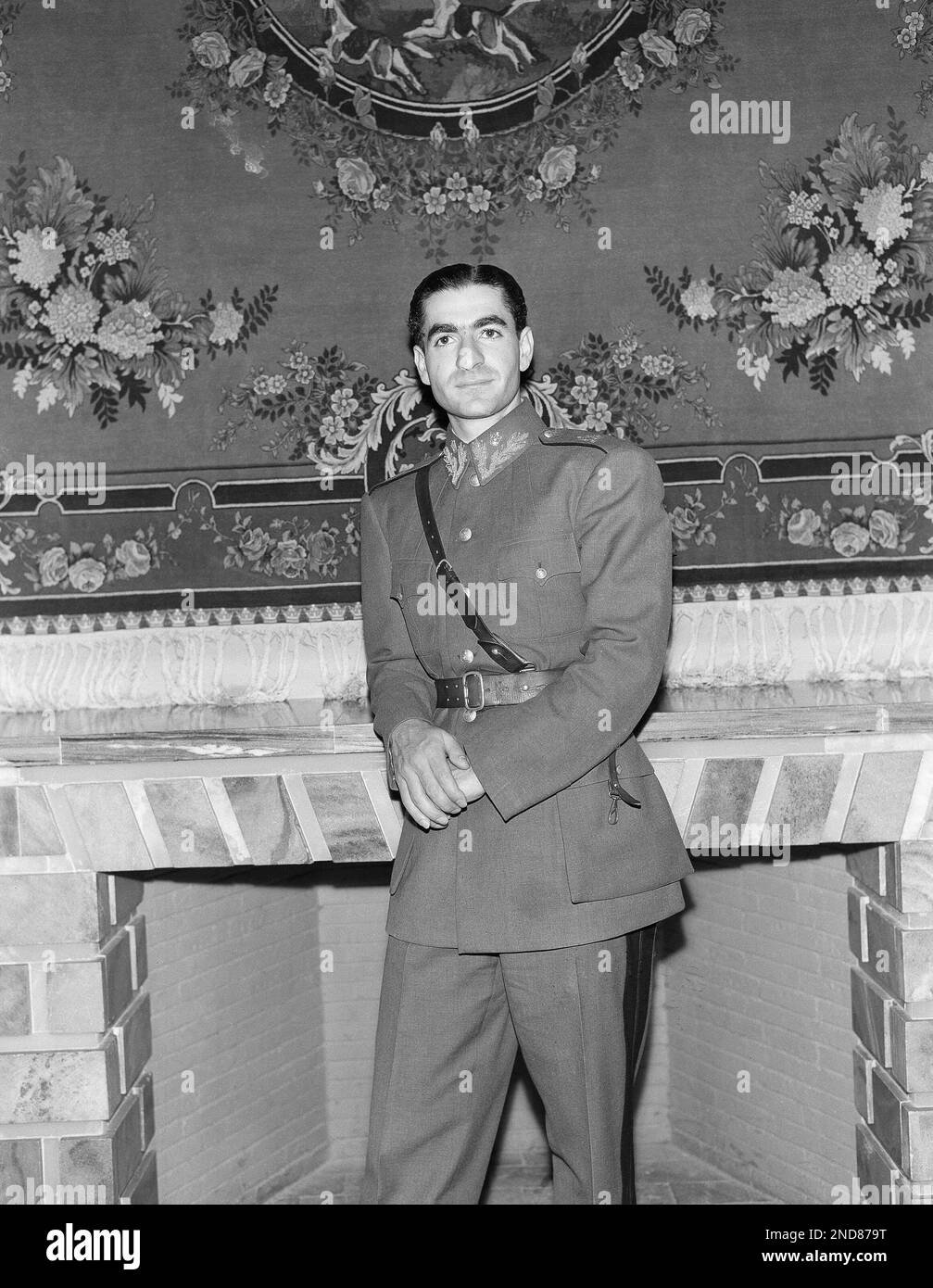Mohammed Reza Shah Pahlavi, King of Iran, stands at the mantle of his ...