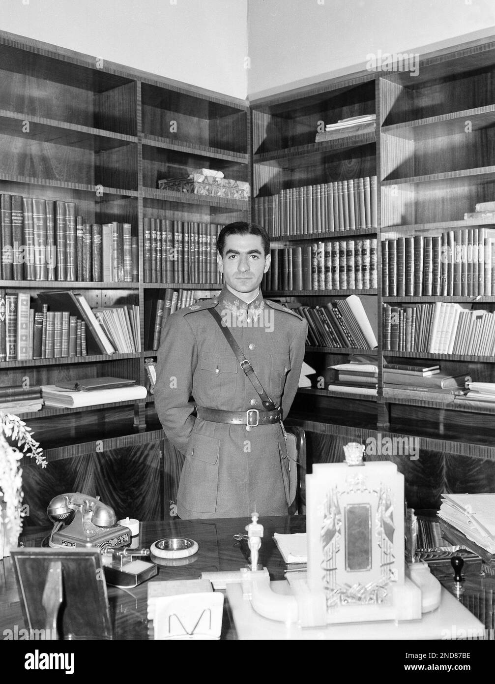Mohammed Reza Shah Pahlavi, King of Iran, stands at the mantle of his ...