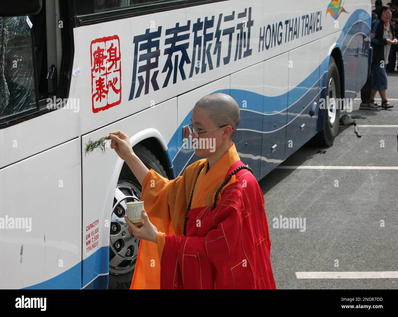A Buddhist monk sprinkles holy water at the bullet-riddled tourist bus ...