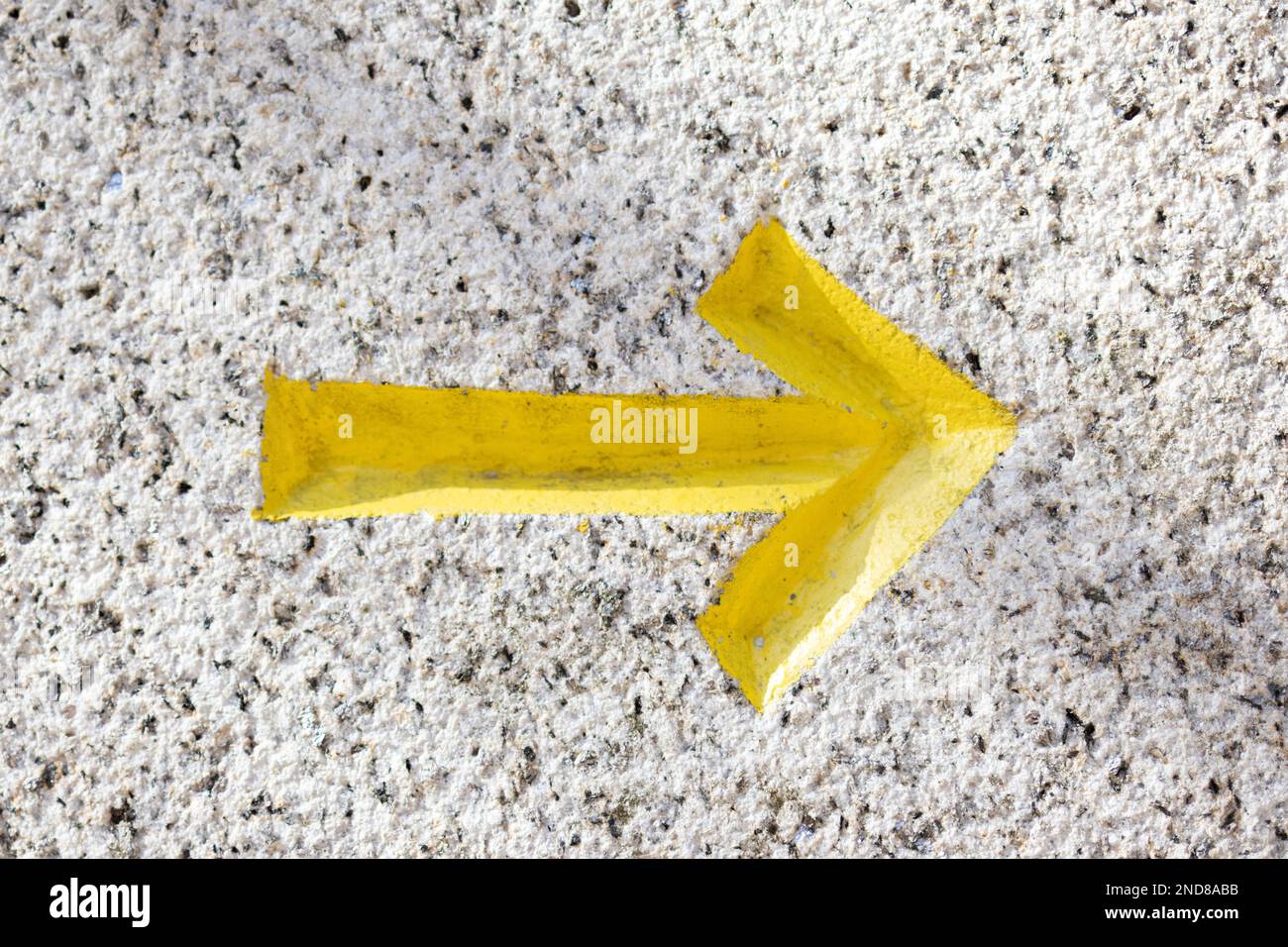 Yellow arrow with chiseled edges on a solid granite stone surface ...