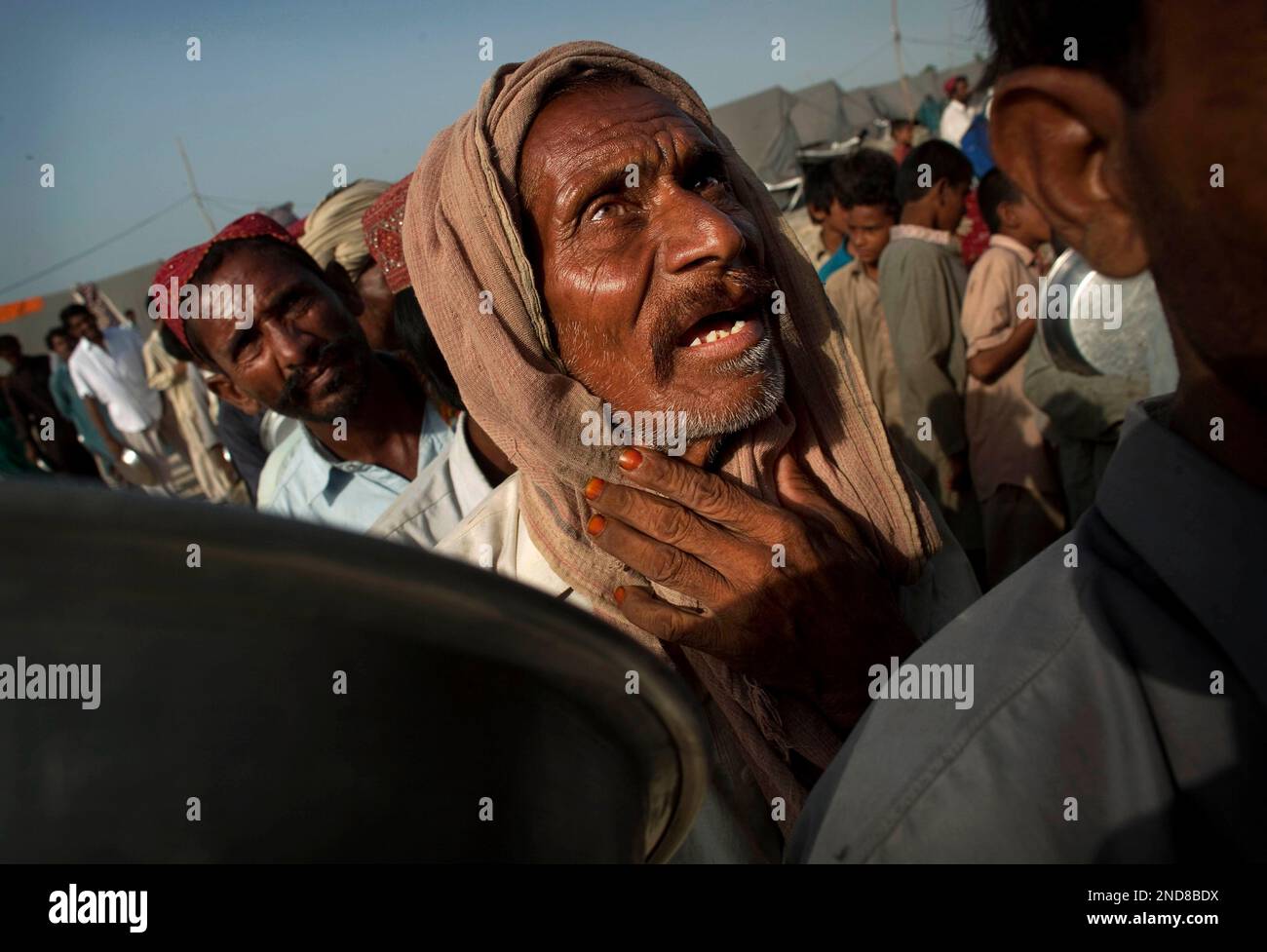 Pakistani men line up as they are given a fresh meal at a camp for ...
