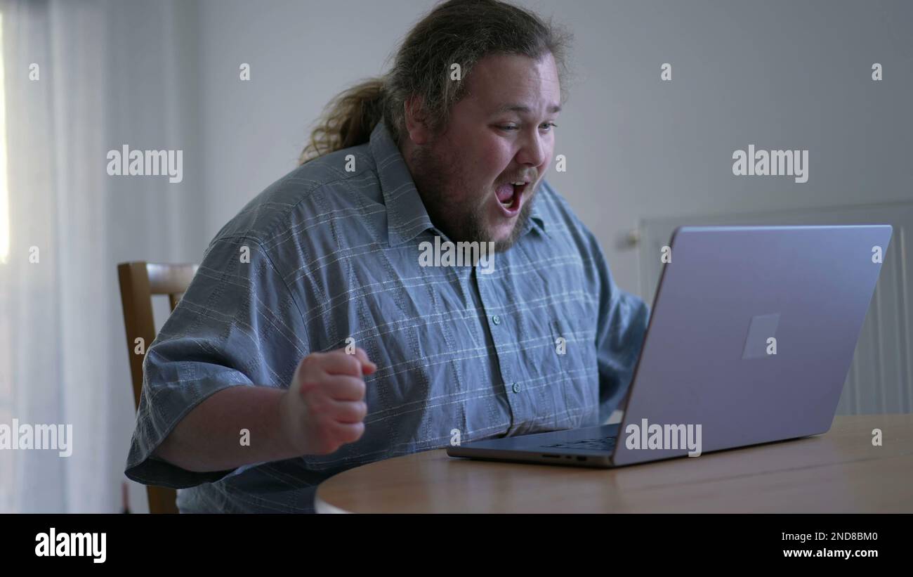 One excited chubby guy celebrating success in front of laptop computer ...