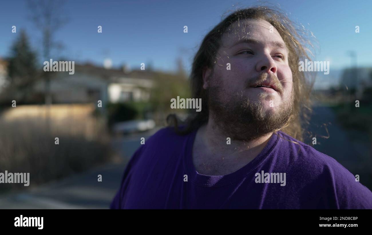 One funny overweight young man shaking head with long hair. Happy free ...