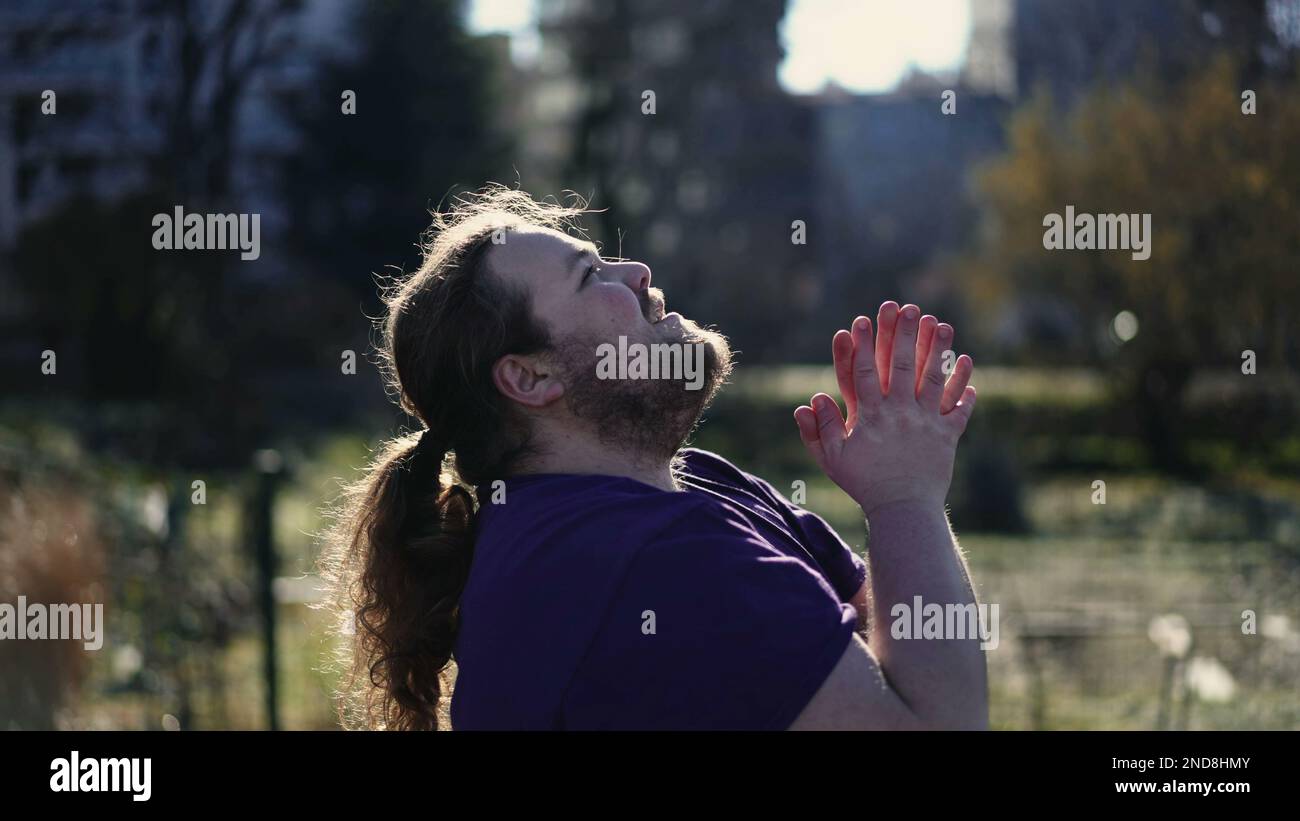 Spiritual Young man standing outside praying to God. Person clenched ...