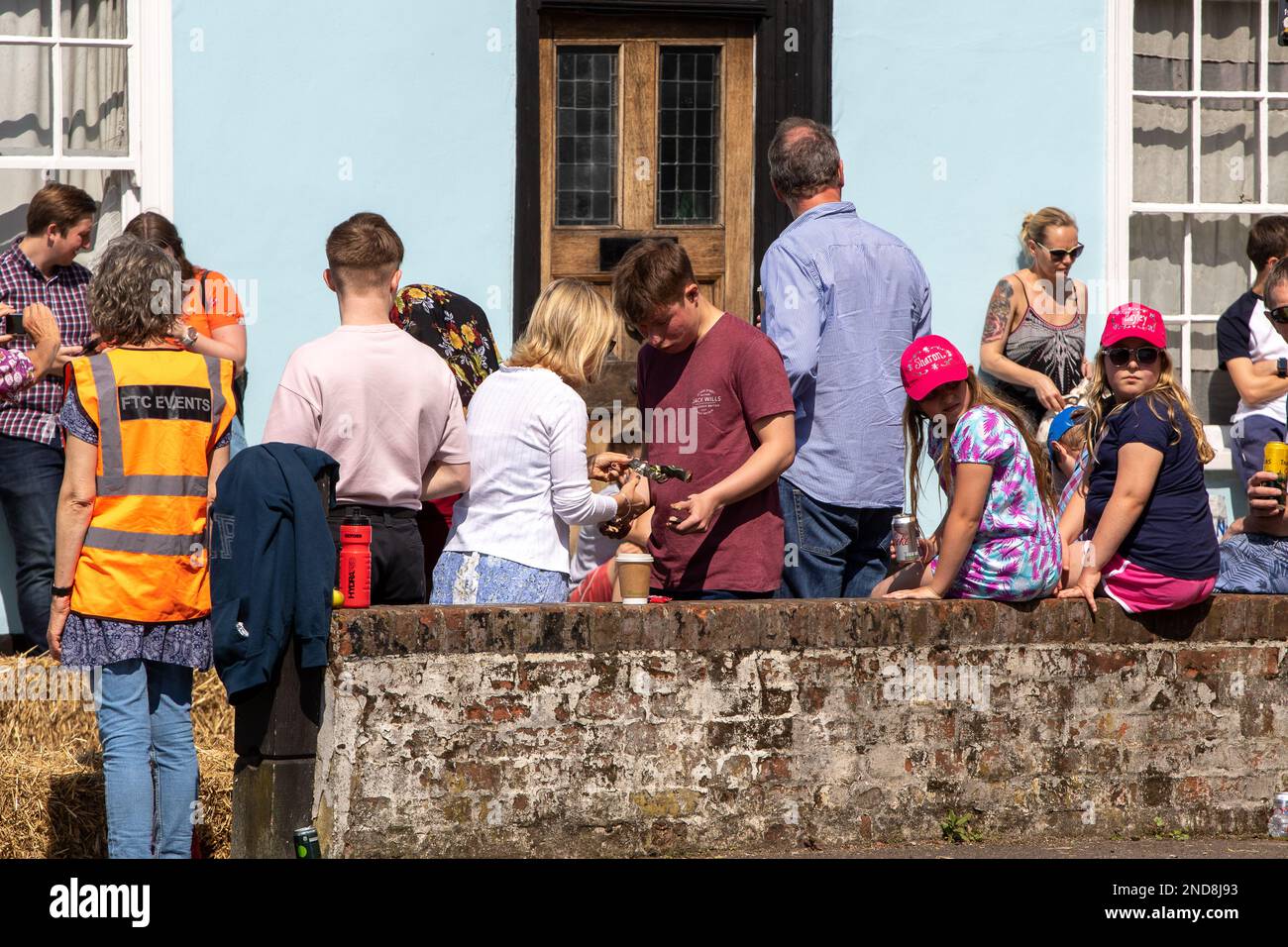 Two young girls in matching red baseball caps sit on a brick wall to ...